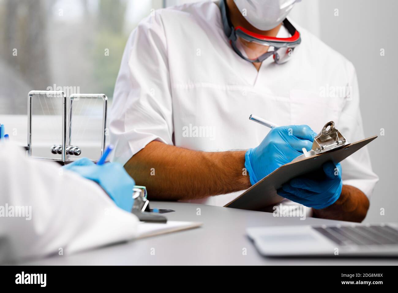 Hands of a doctor writing something on clipboard while sitting at ...