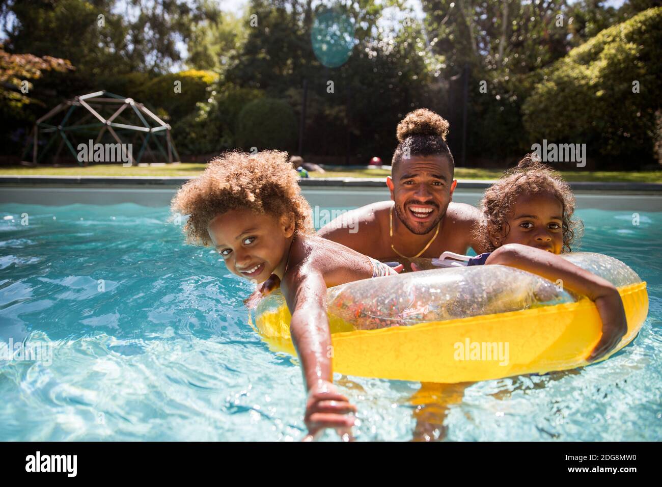 Portrait Happy Father And Daughters Playing In Sunny Swimming Pool