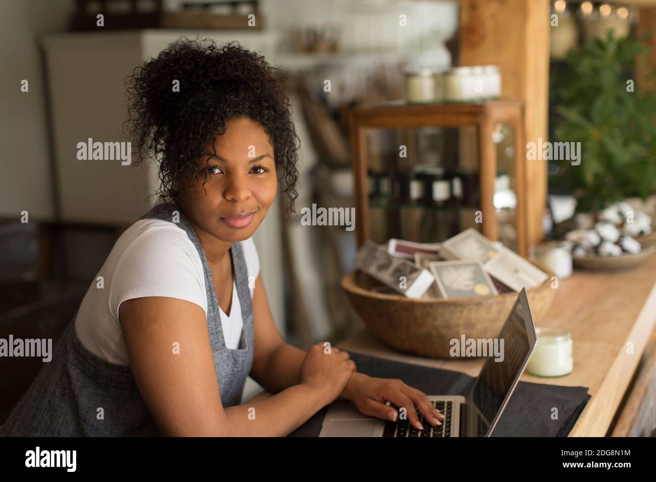 Portrait confident female shop owner using laptop in plant nursery ...