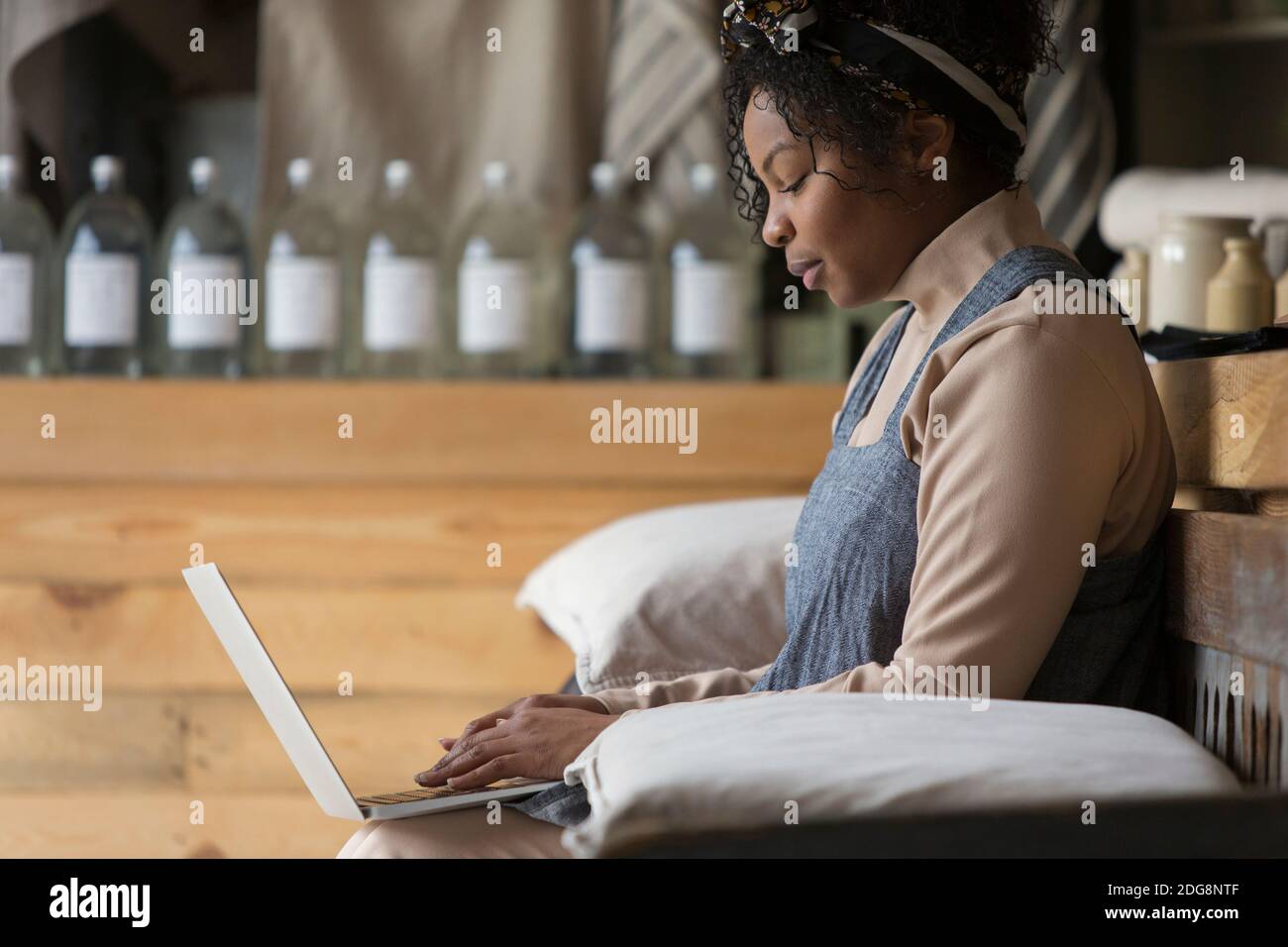Female shop owner using laptop on bench Stock Photo - Alamy