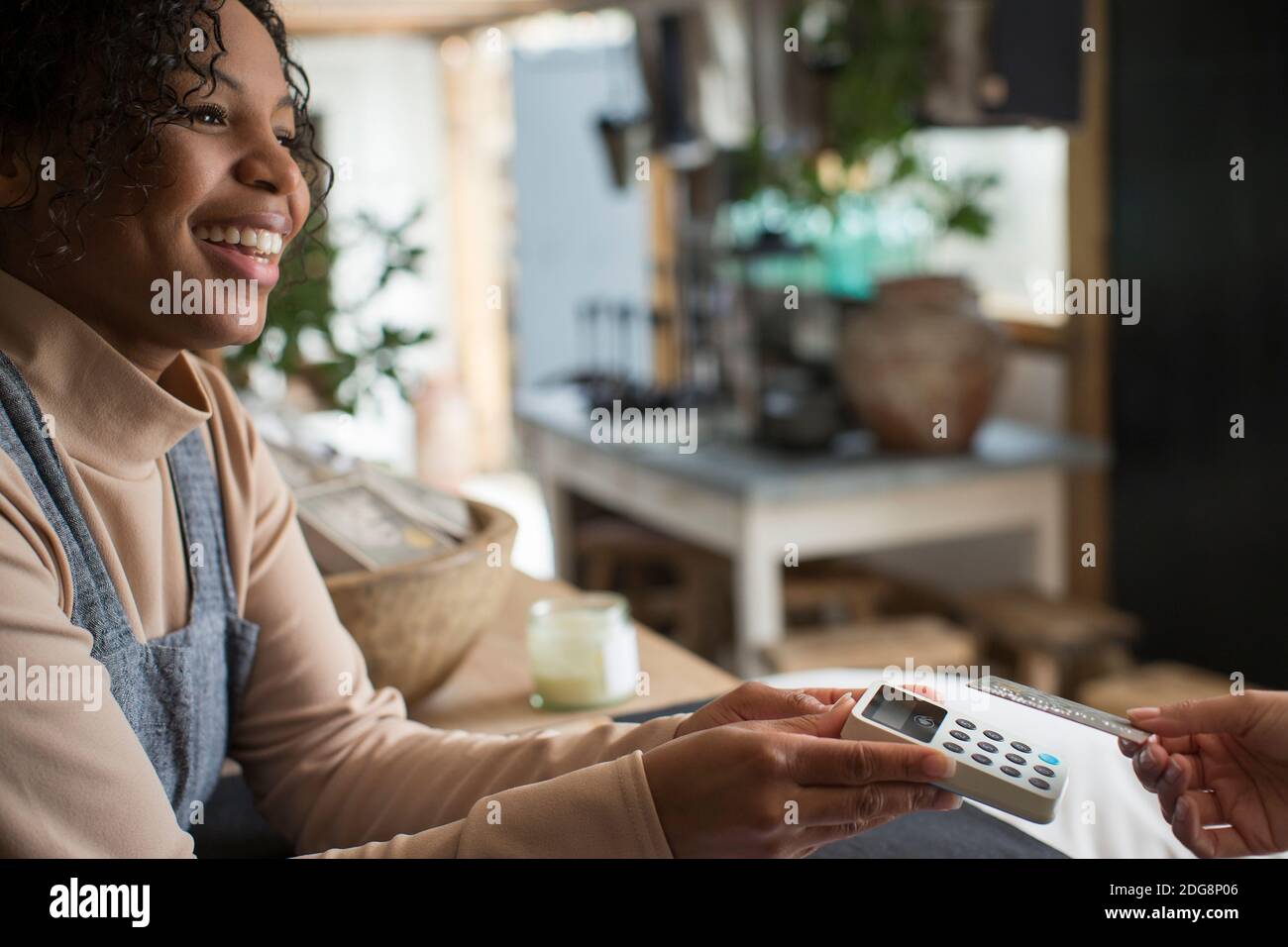 Friendly female shop owner holding credit card reader for customer ...