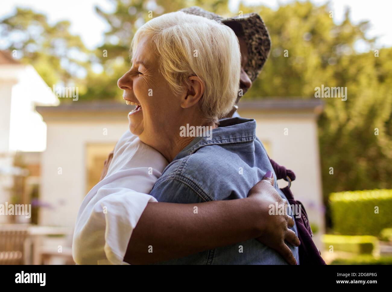 Happy senior women friends hugging on patio Stock Photo - Alamy