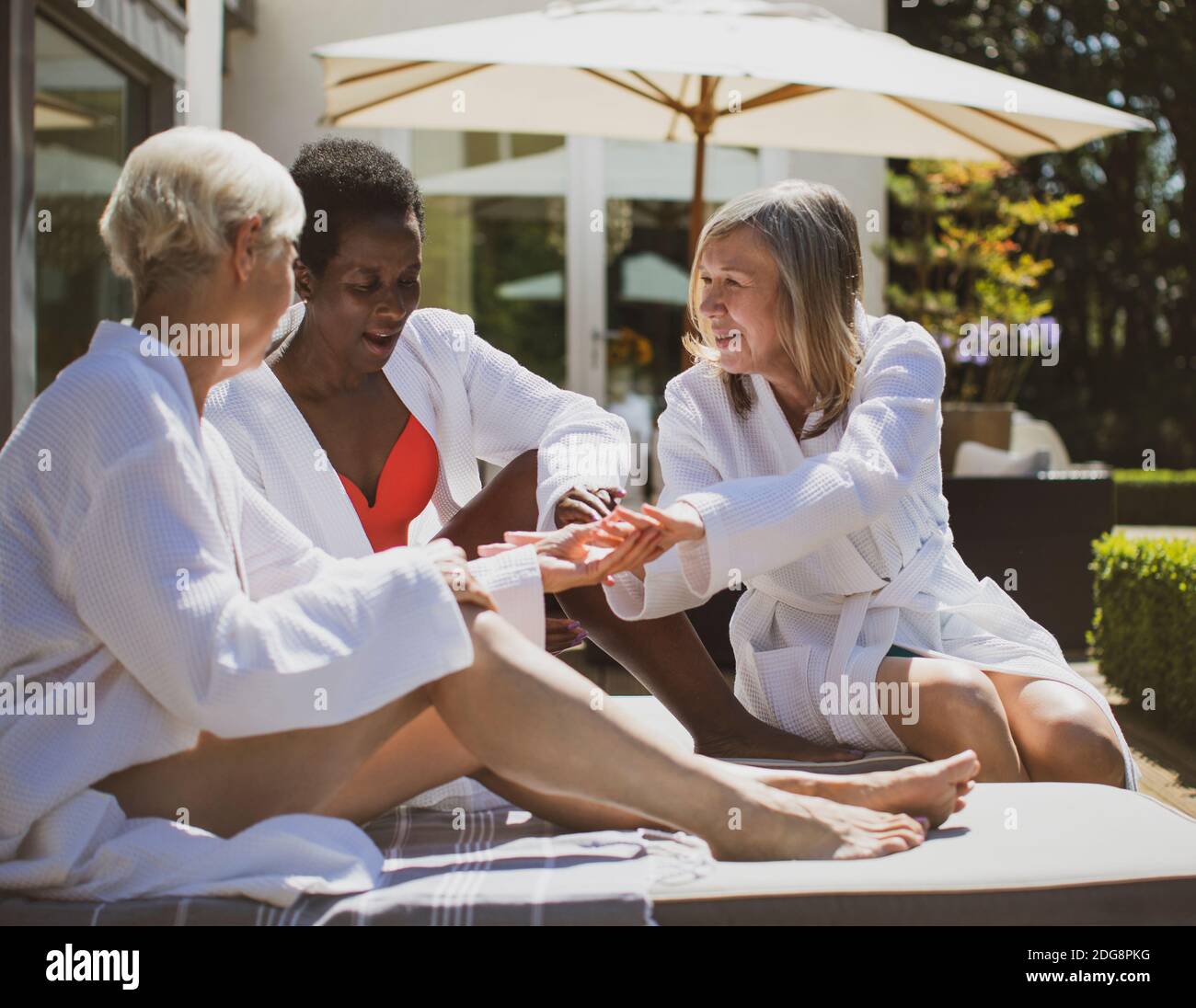 Senior women friends in spa bathrobes on sunny hotel patio Stock Photo ...