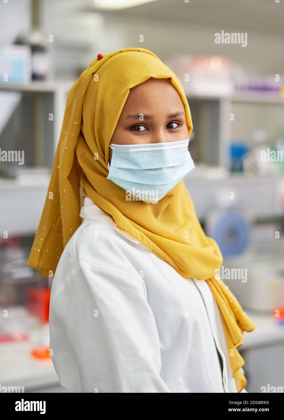 Portrait confident female scientist in hijab and face mask in ...
