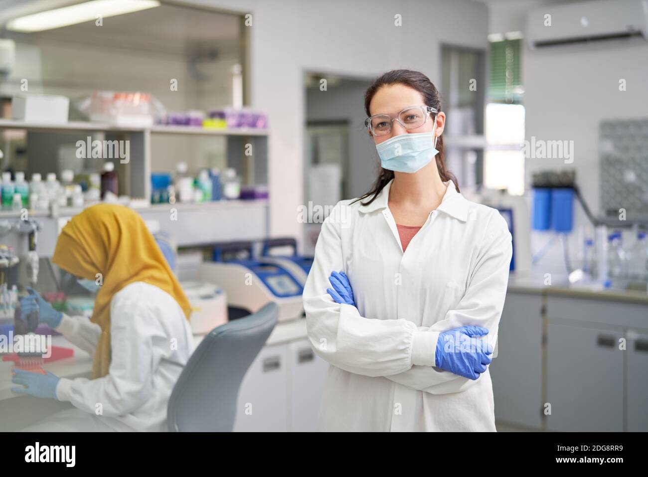 Portrait confident female scientist in face mask and rubber gloves ...