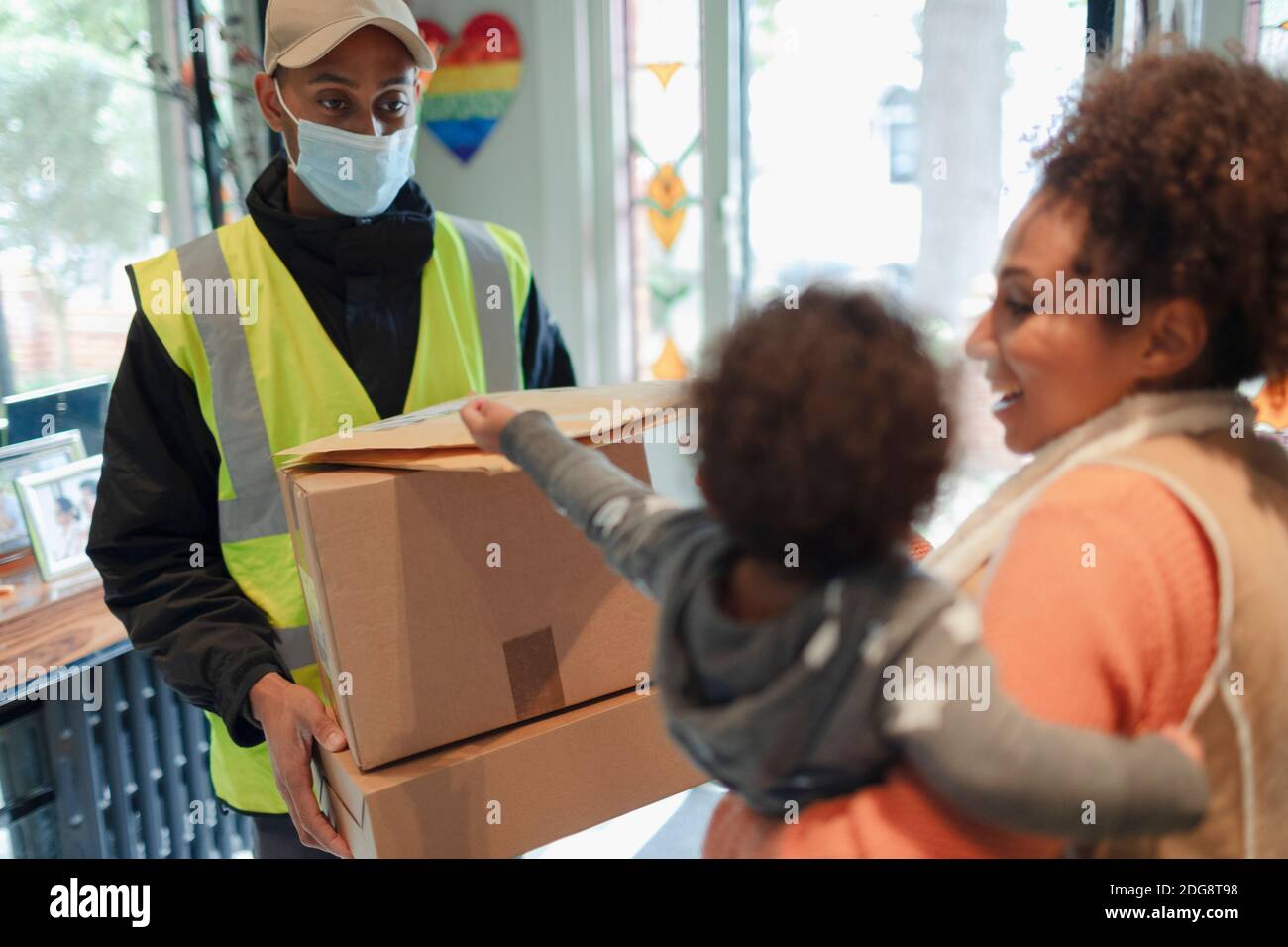 Mother and baby daughter receiving packages from delivery man in mask ...