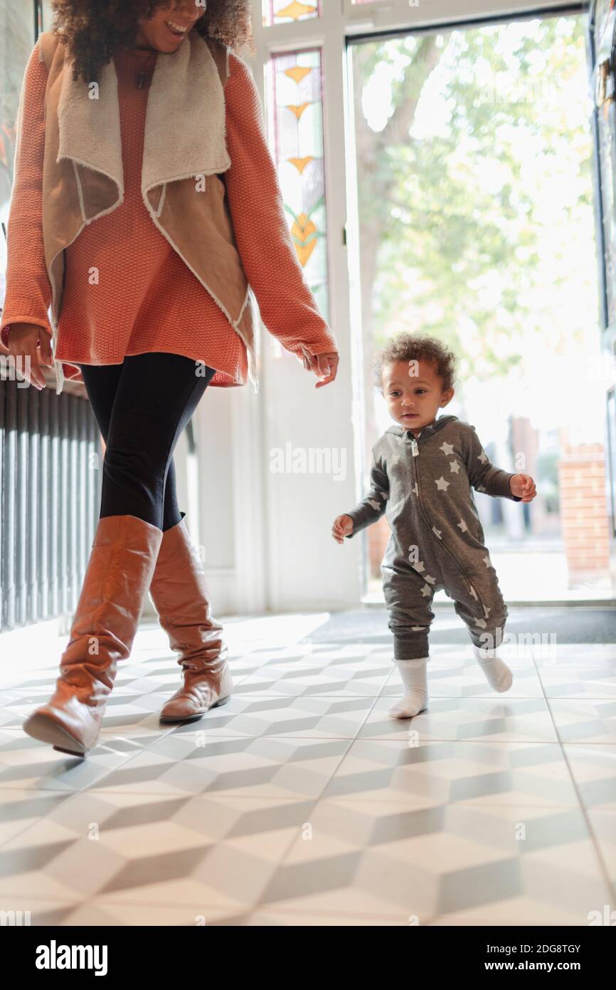 Cute baby daughter following mother in entry corridor Stock Photo - Alamy