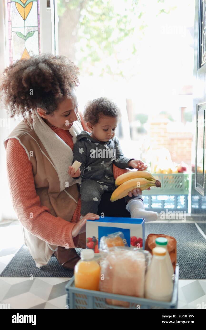 Mother and baby daughter receiving grocery delivery at front door Stock ...