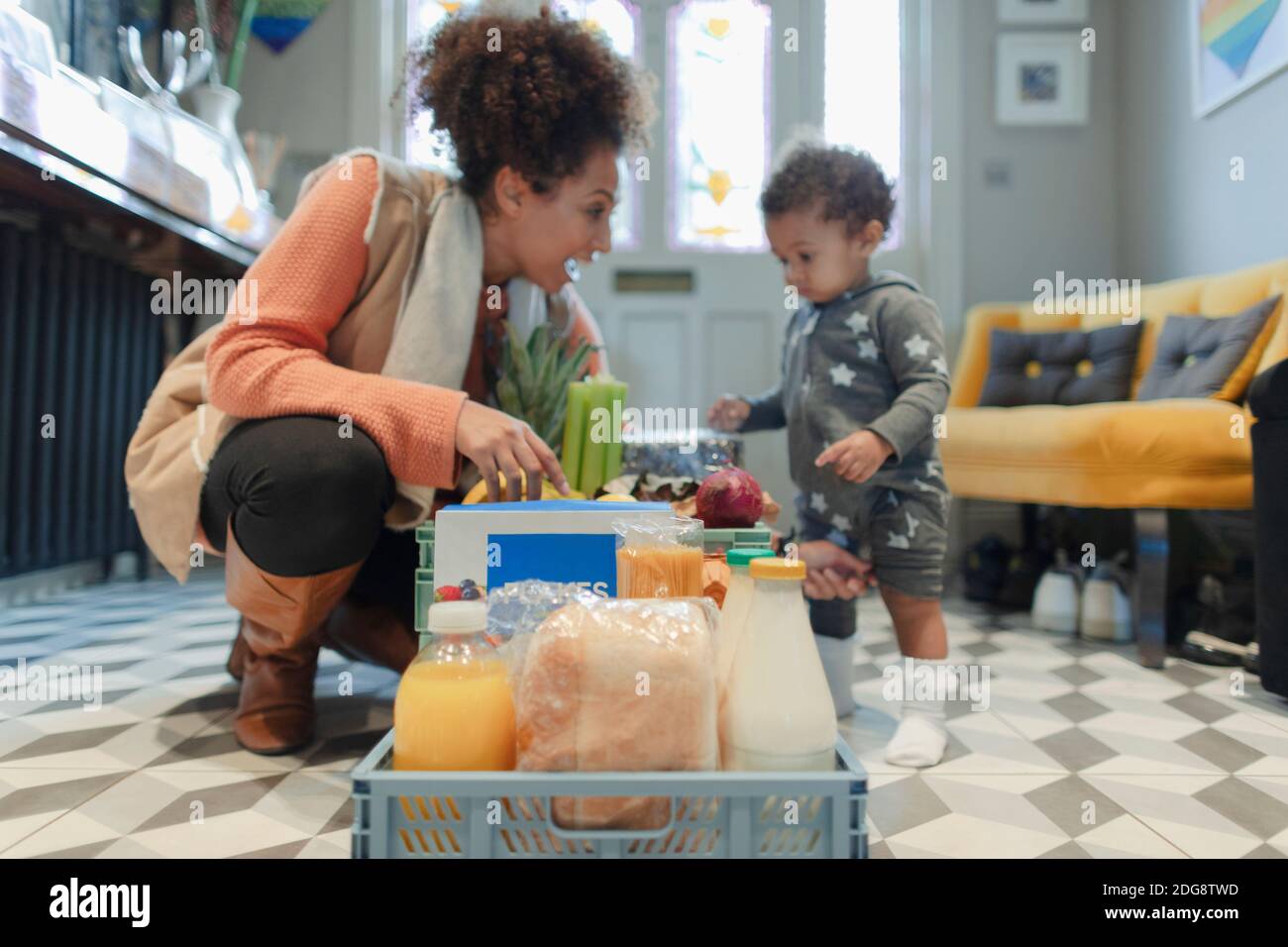 Mother and baby daughter receiving grocery delivery in foyer Stock ...