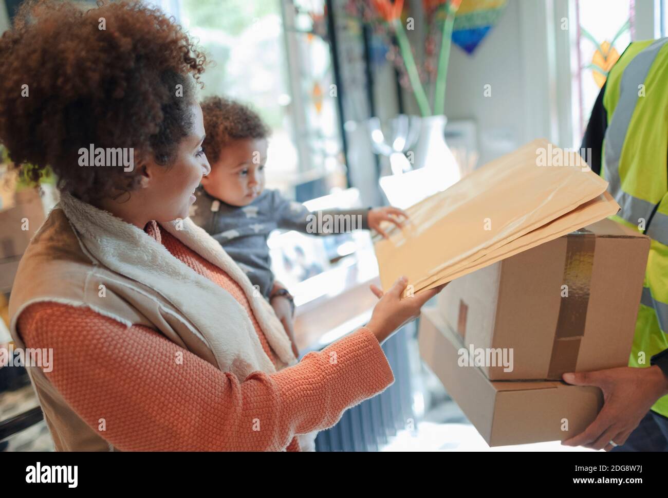 Mother and baby daughter receiving package from delivery person Stock ...