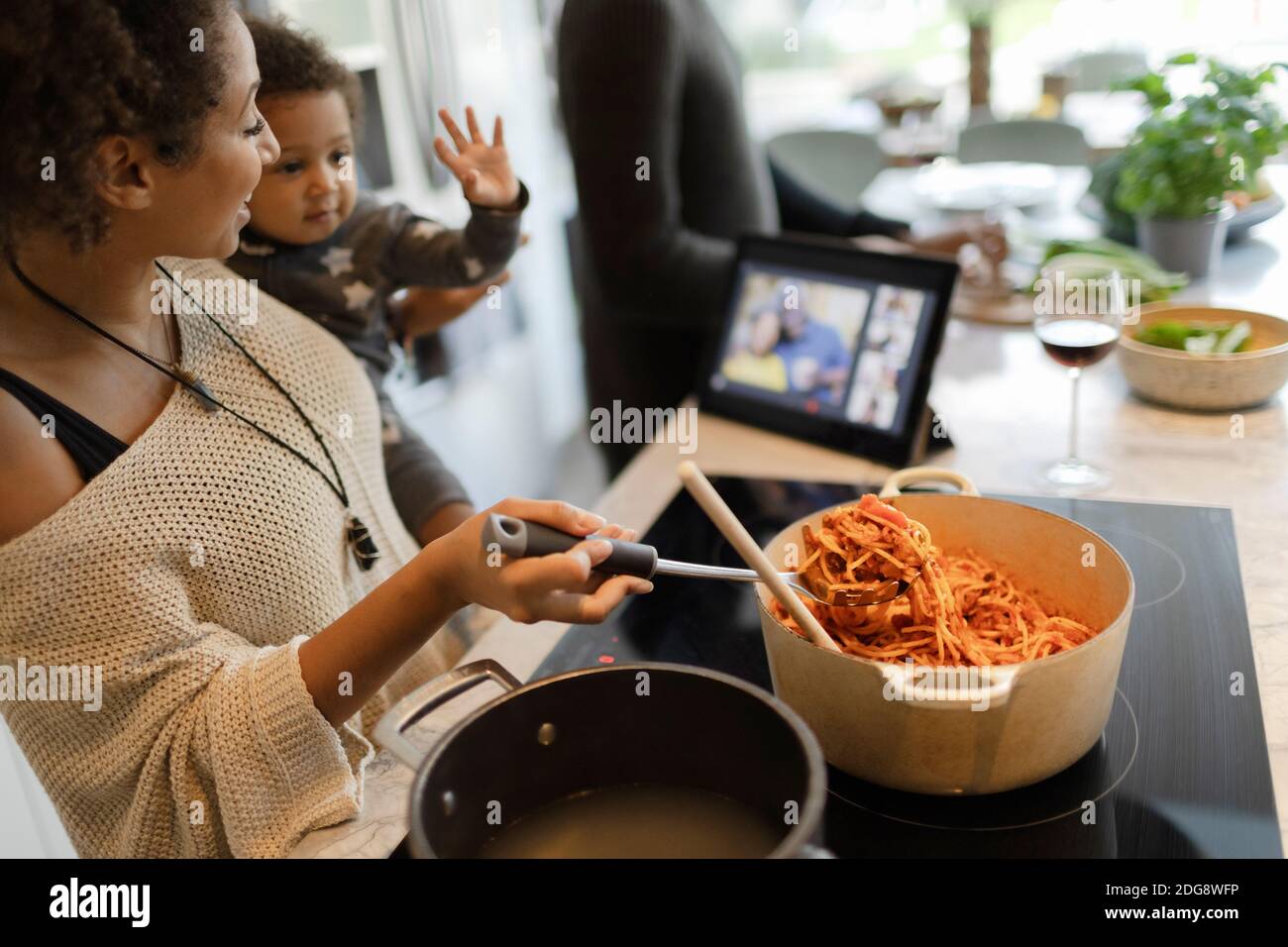 Mother and baby daughter cooking spaghetti and video chatting Stock ...