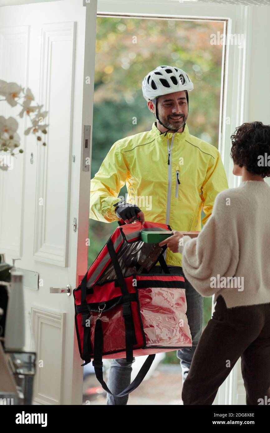 Woman receiving pizza delivery from delivery man at front door Stock ...