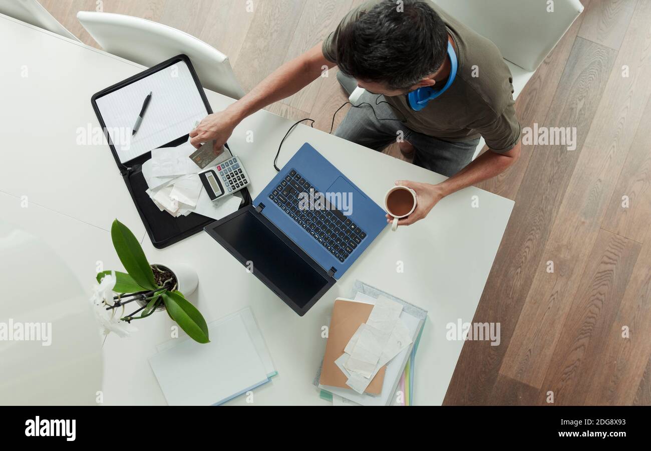 Man with receipts paying bills at laptop Stock Photo - Alamy