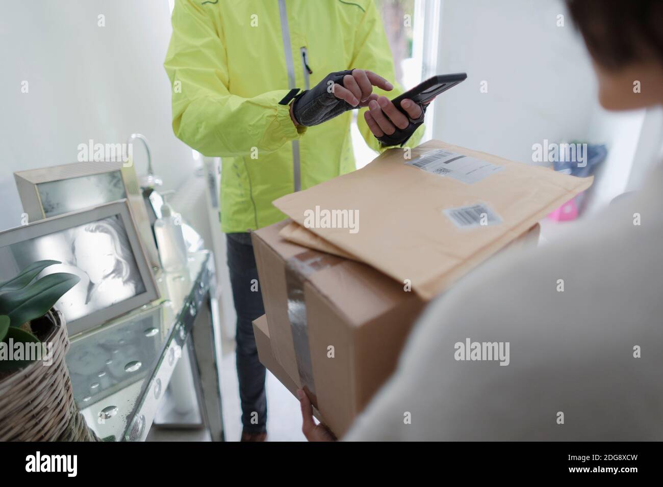 Woman receiving packages from delivery man with smart phone Stock Photo ...