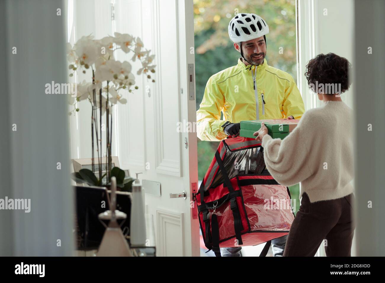 Friendly courier delivering pizza to woman at front door Stock Photo ...