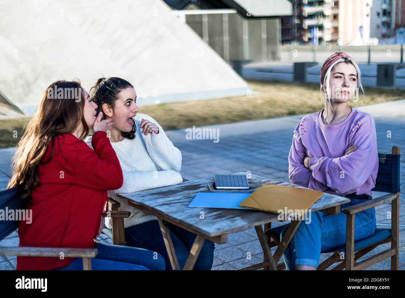 Two gossip friends criticizing another woman outside Stock Photo - Alamy