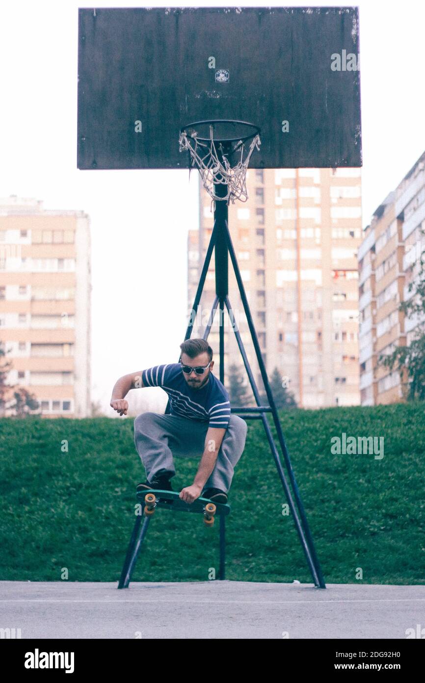 A cool man playing with his skateboard on a basketball court in ...