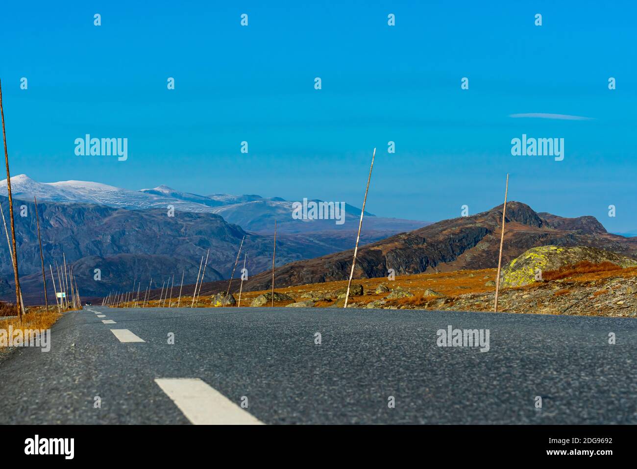 Asphalt road through the mountain highlands, with tall wooden marking ...