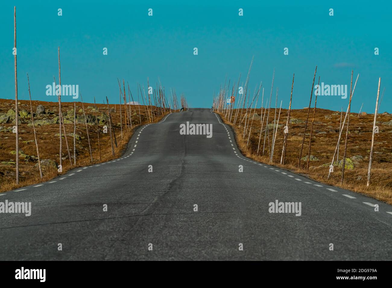Asphalt road through the mountain highlands, with tall wooden marking ...