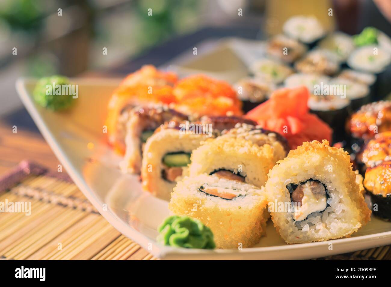 Sushi roll set on white square plate outdoor cafe Stock Photo - Alamy