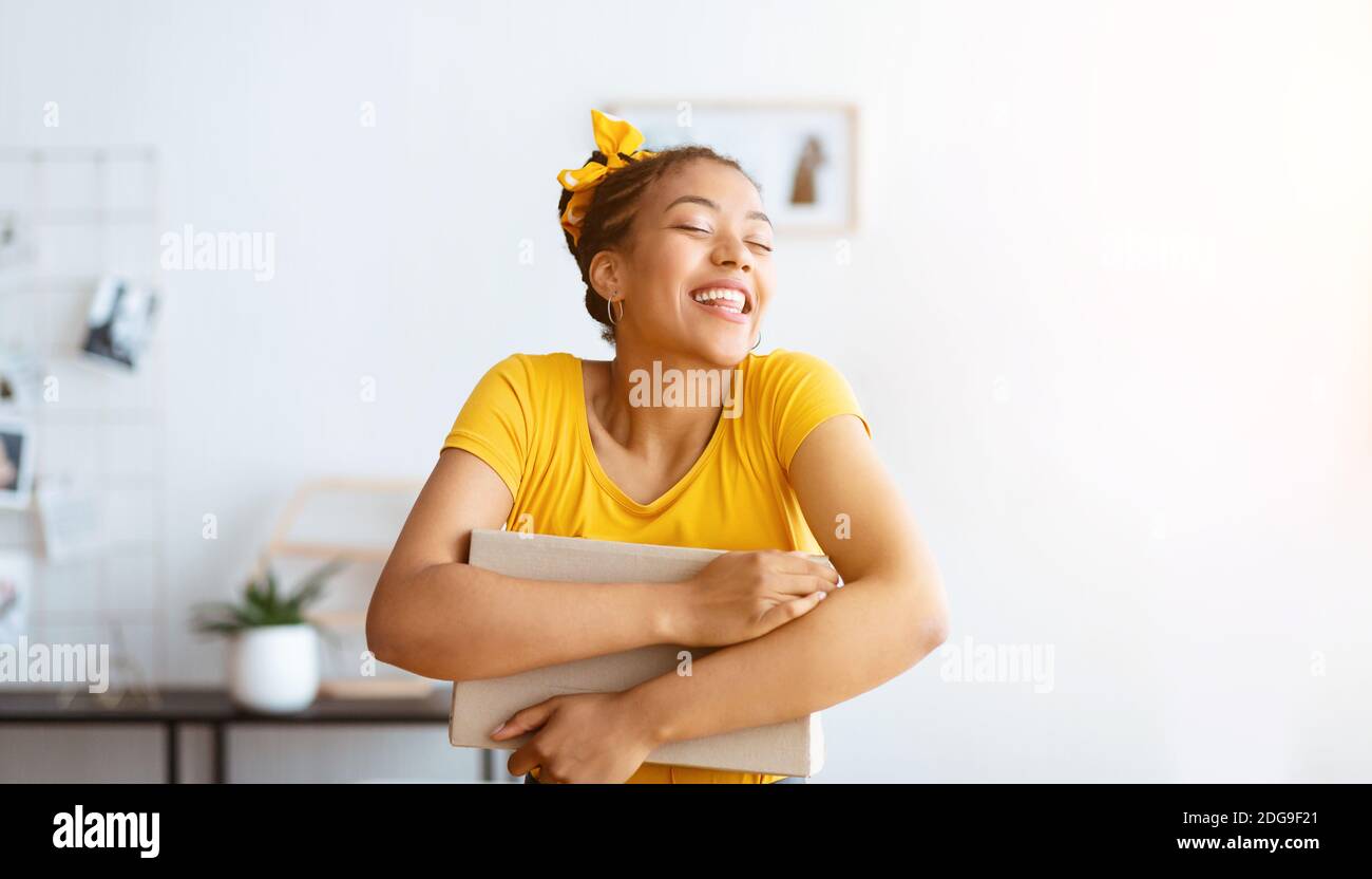Excited black woman hugging and embracing carton box Stock Photo - Alamy