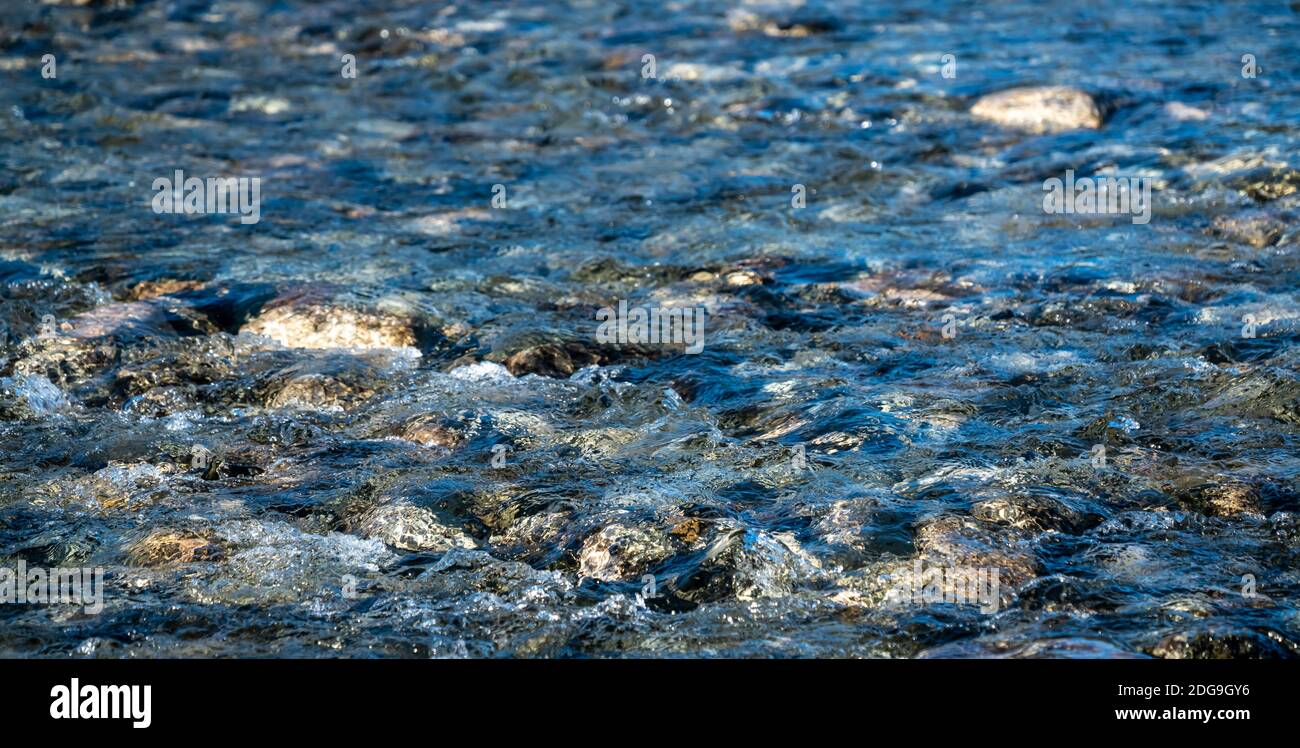 Crystal clear glacial melting water running over smooth rocks and ...