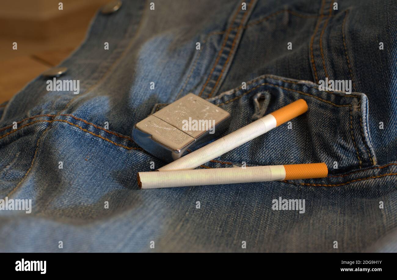 Tobacco cigarettes and metal lighter on a jeans jacket Stock Photo - Alamy