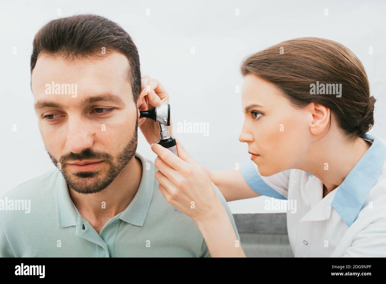 ENT doctor checking adult male ear using an otoscope. Hearing exam for ...