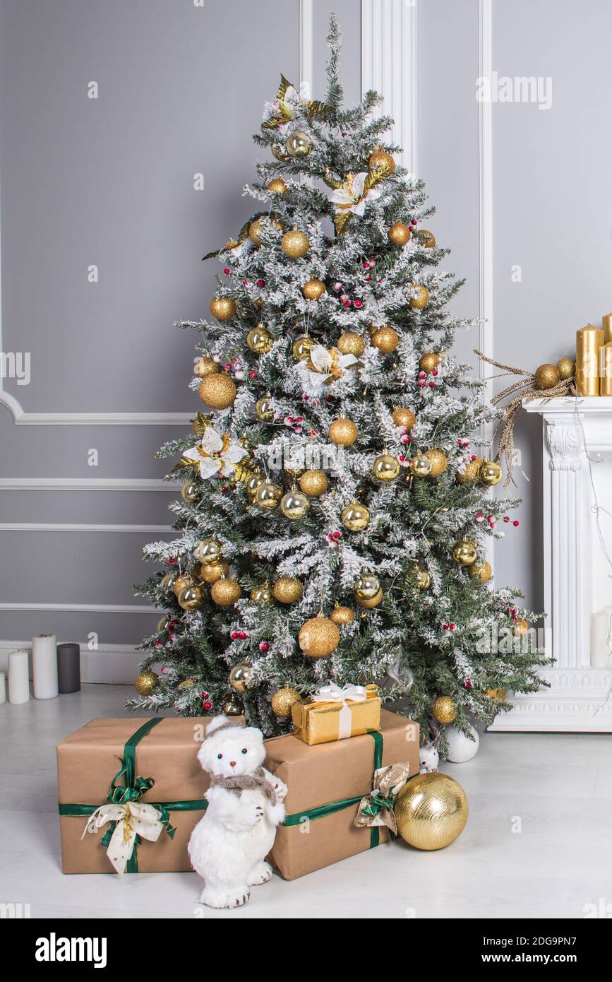 Big beautiful New Year tree with gifts in a white decorated hall for ...