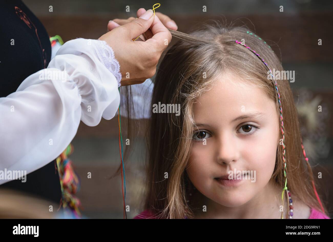 Chinese woman braiding Caucasiuan girl hair on the street in Feng Huang ...