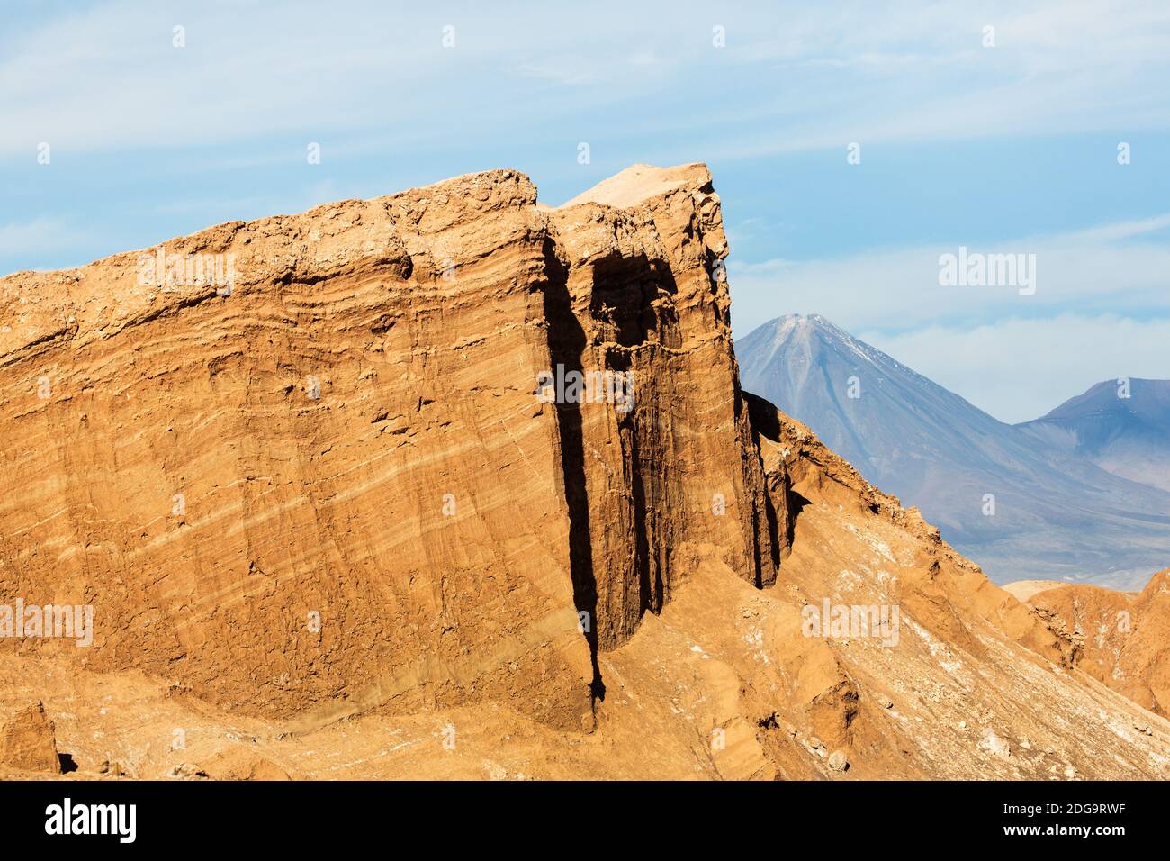 Volcan Licancabur rises behind massive eroded orange cliffs in the ...