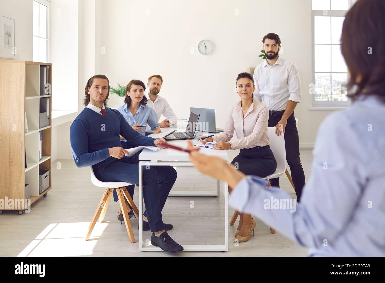 Group of office workers sitting and listening to colleague making ...