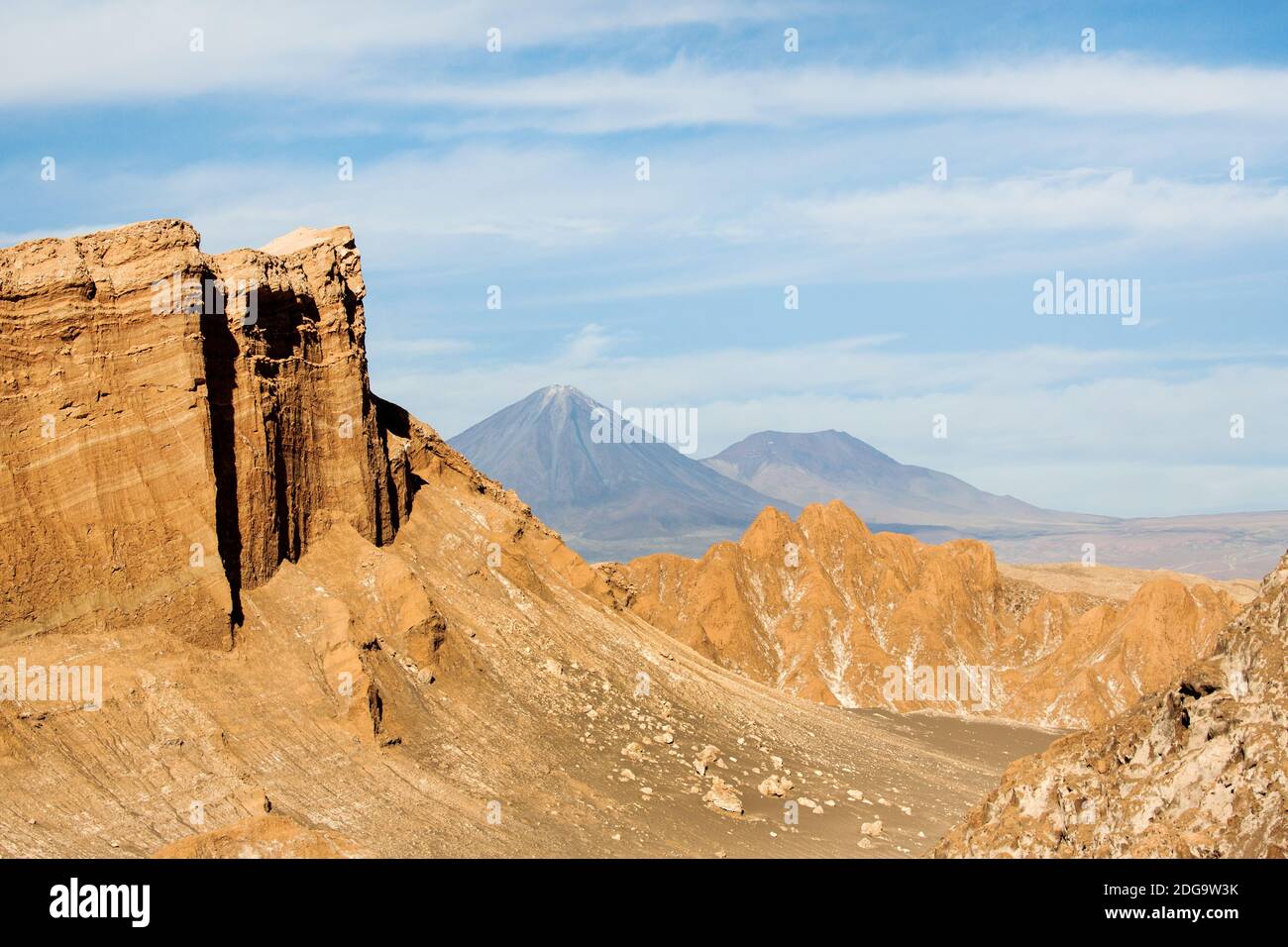 Volcan Licancabur rises behind massive eroded orange cliffs in the ...