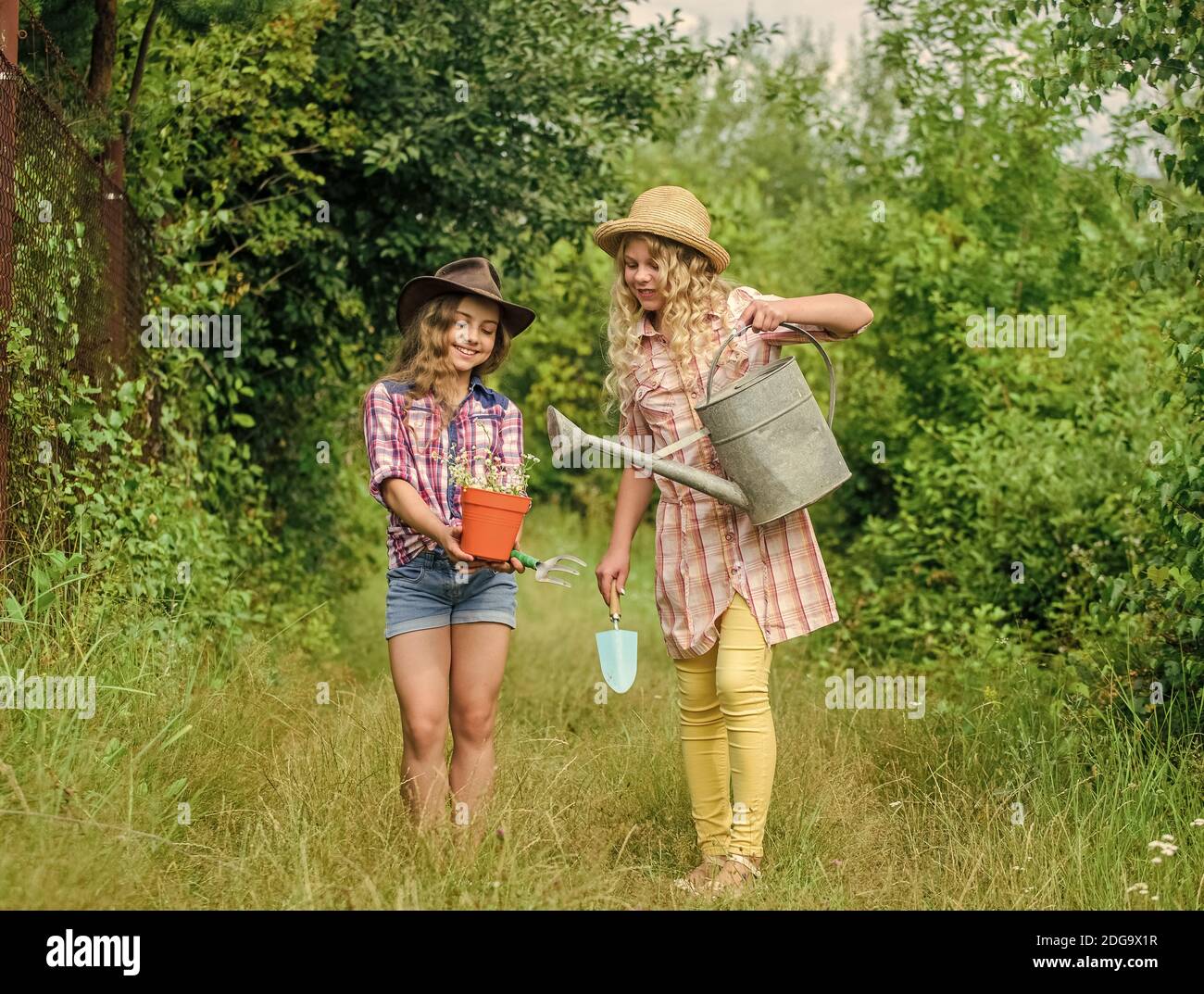 Girls in hats planting plants. Rustic children nature background ...