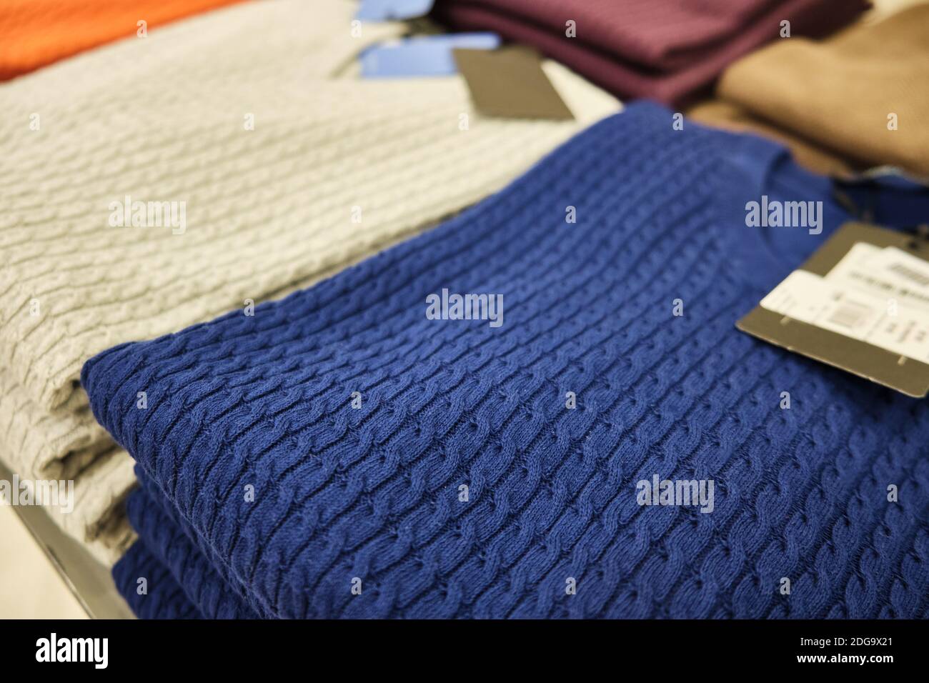Men knitted sweaters in pastel colors stacked on store counter Stock ...