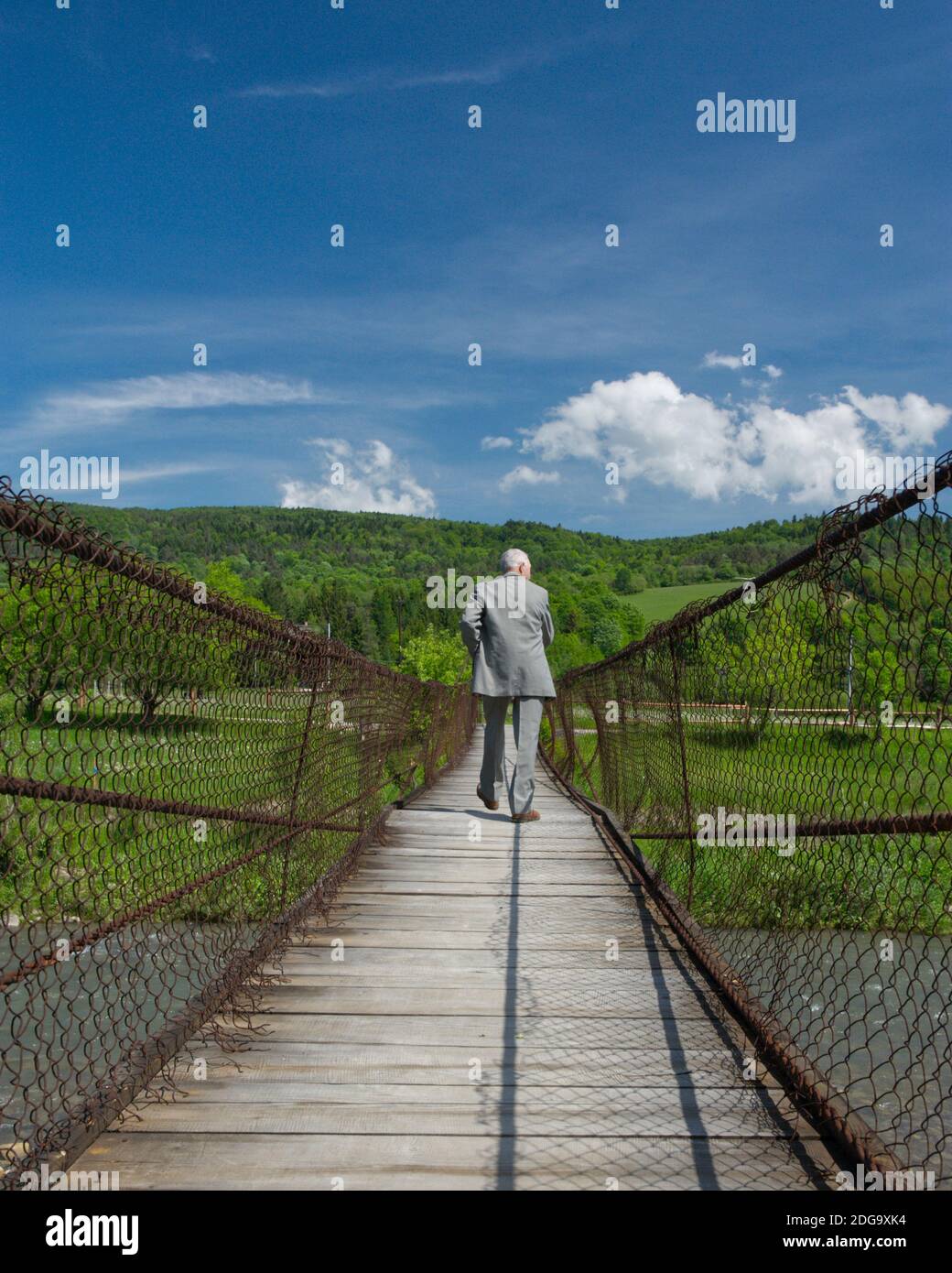 old man crossing the suspension bridge over the river Stock Photo - Alamy
