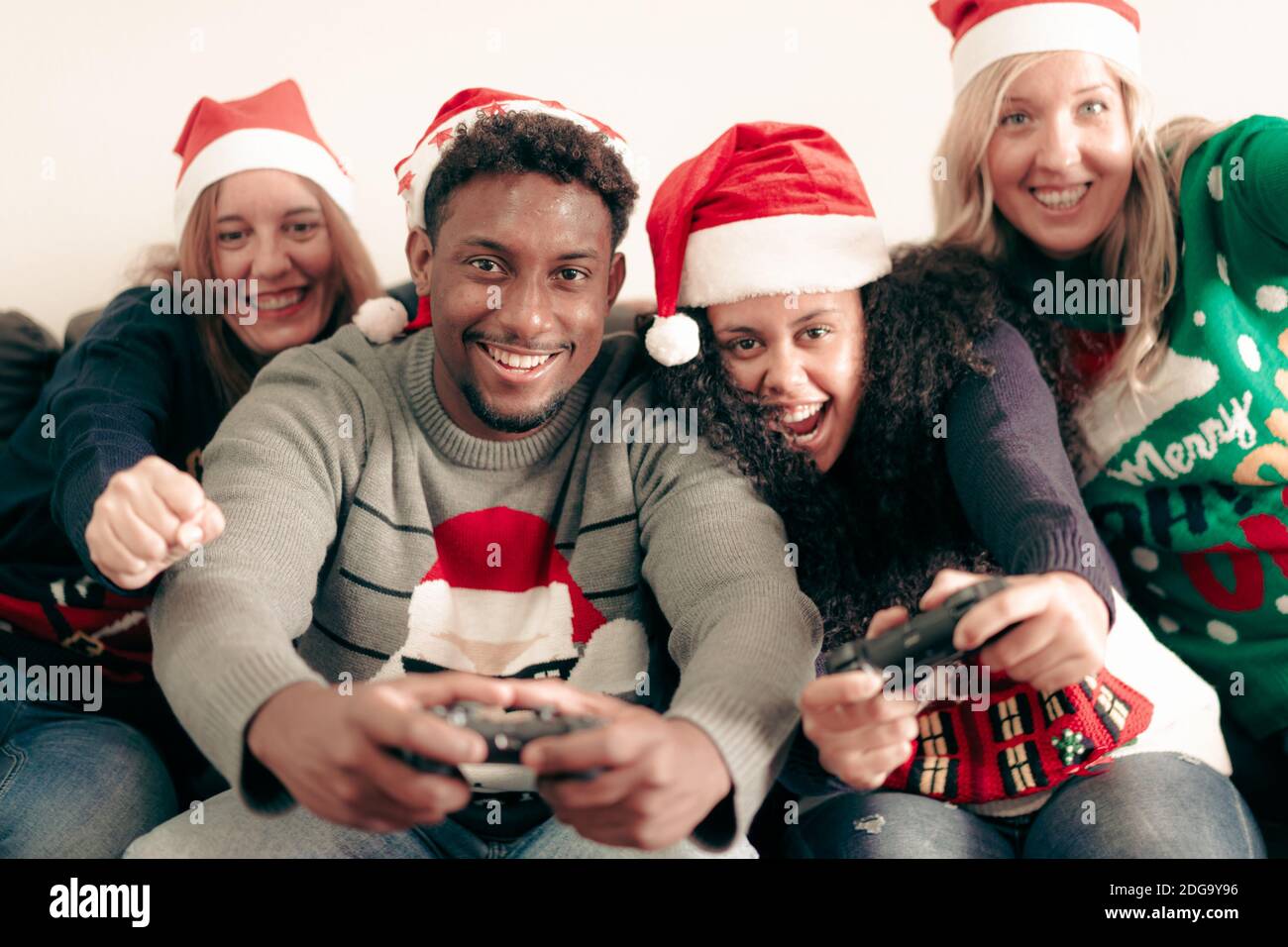 Millennial people having fun with video games console on christmas time ...
