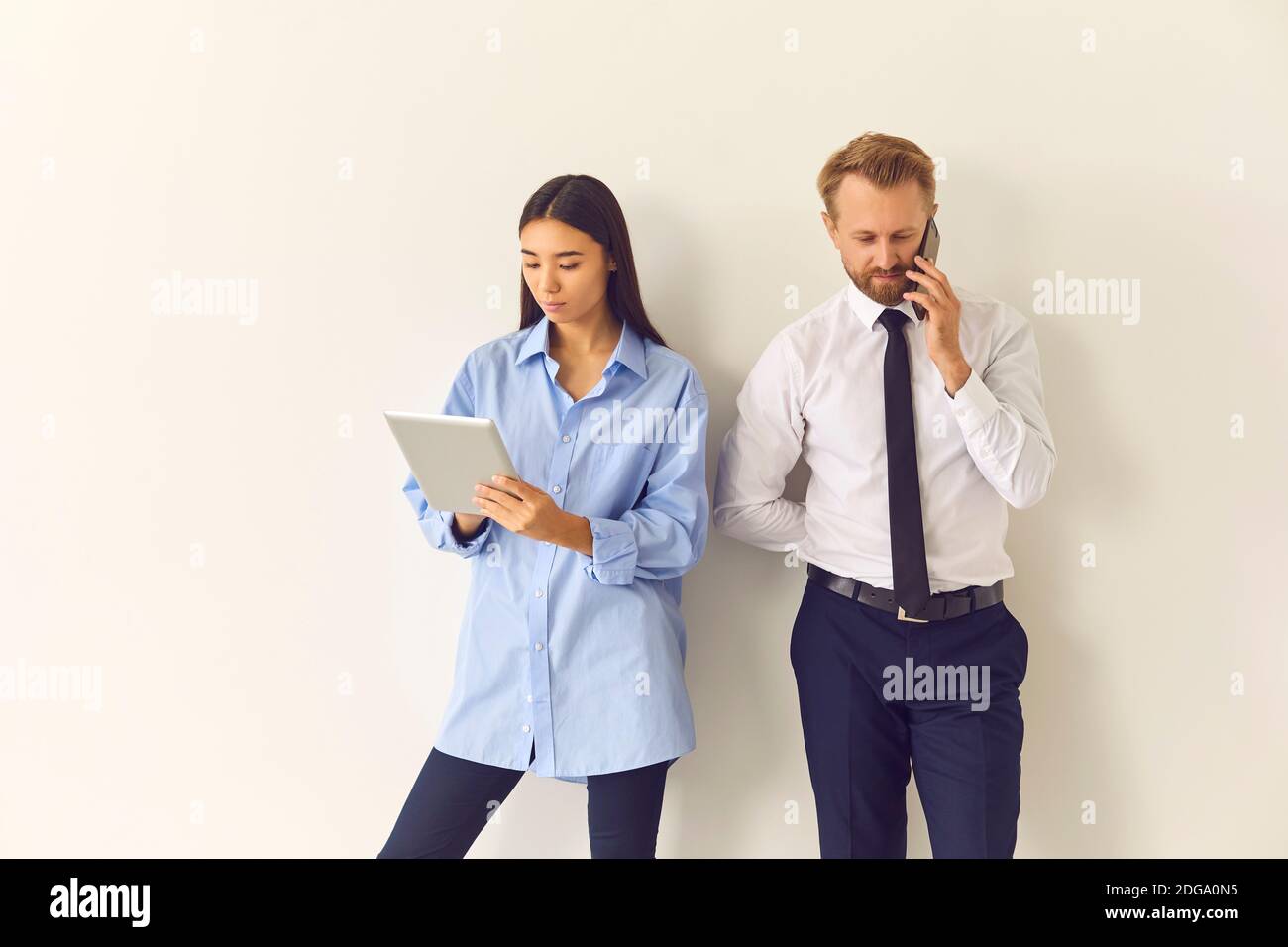 Two coworkers using gadgets during break at work completely ignoring ...
