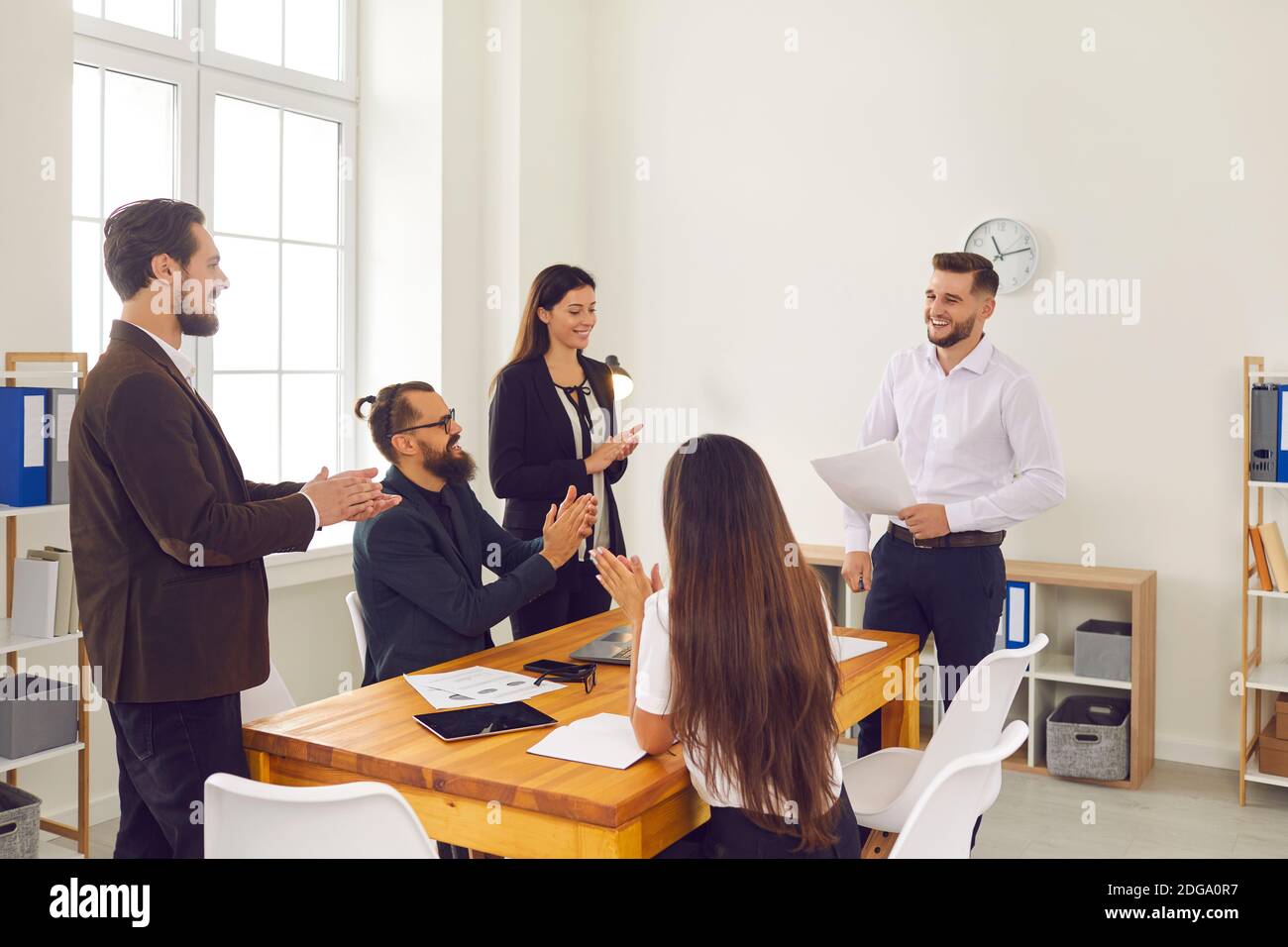 Group of smiling business people applauding to coworker after ...