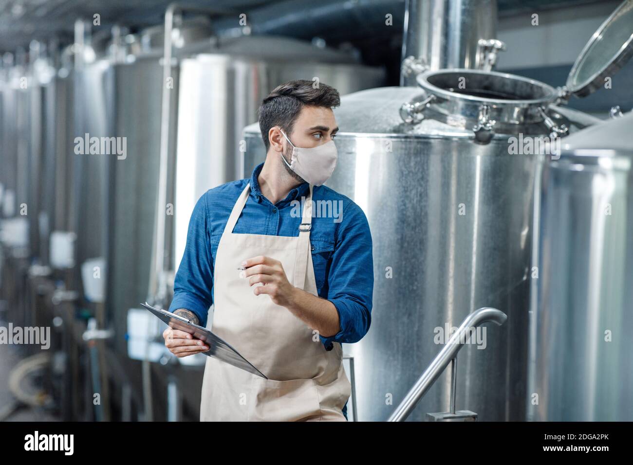 Factory employee works with equipment for industrial beer production ...