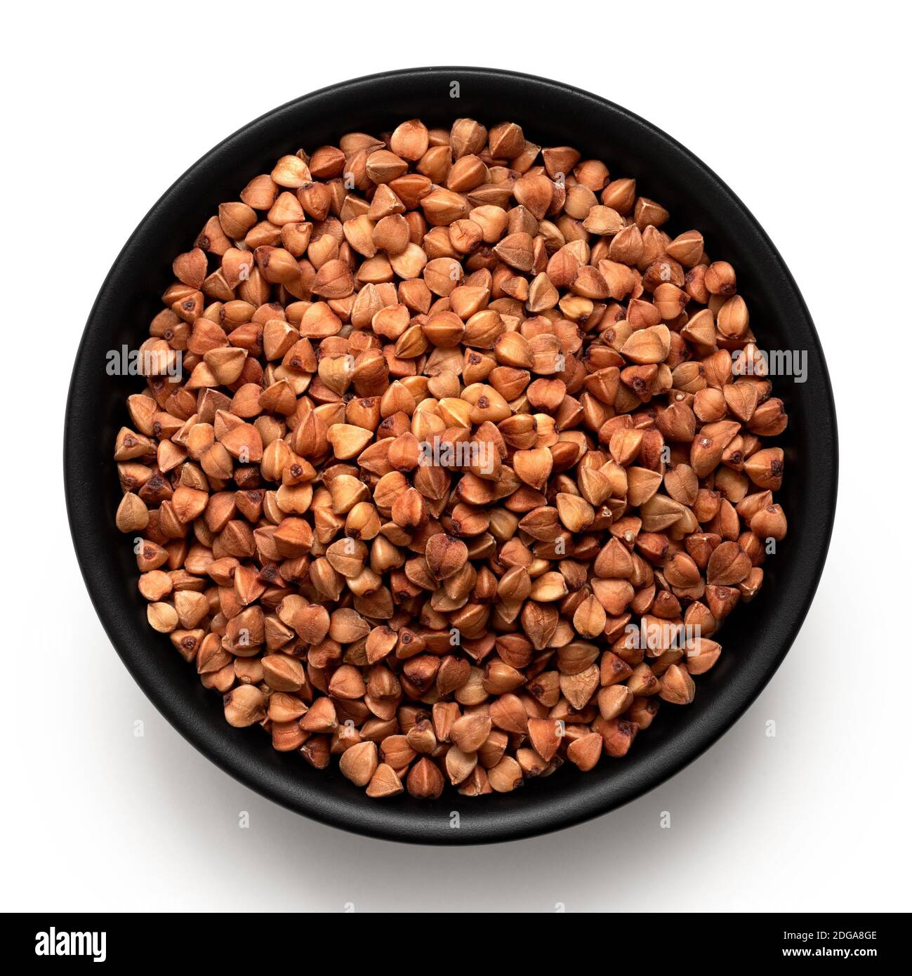 Raw toasted buckwheat in a black ceramic bowl isolated on white.Top ...