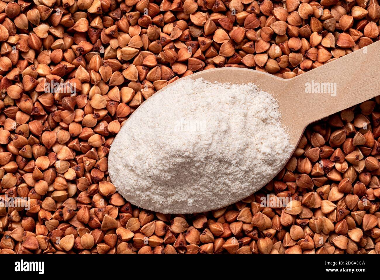 Spoonful of buckwheat flour on top of raw toasted buckwheat. Top view ...