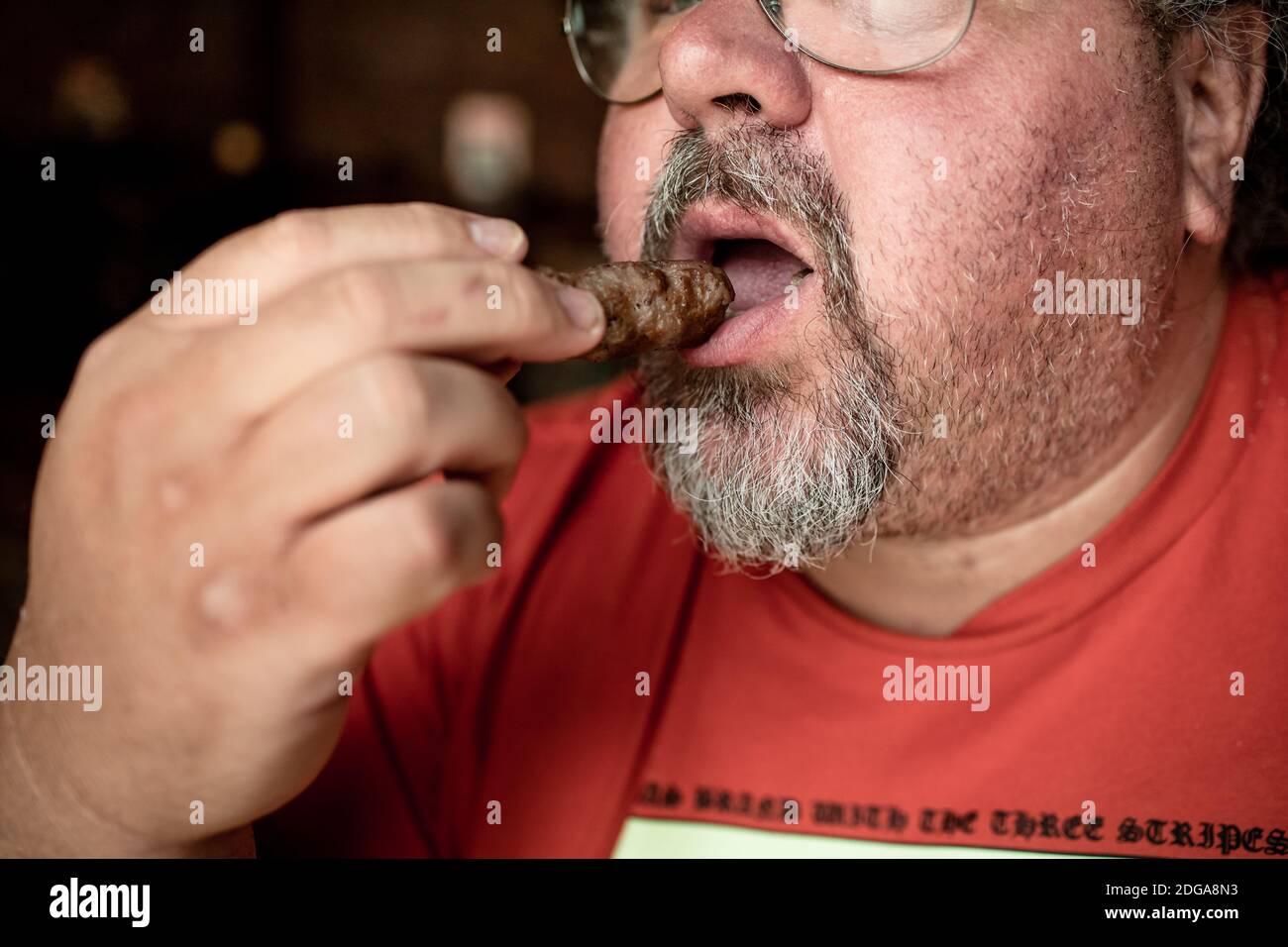 Close-up of obese man mouth eating grilled meat with joy. Unhealthy ...
