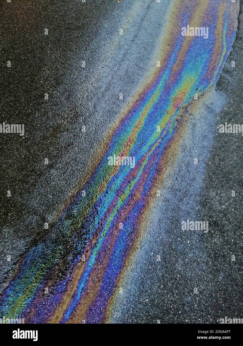 A closeup vertical shot of colorful gasoline fuel stain on asphalt ...
