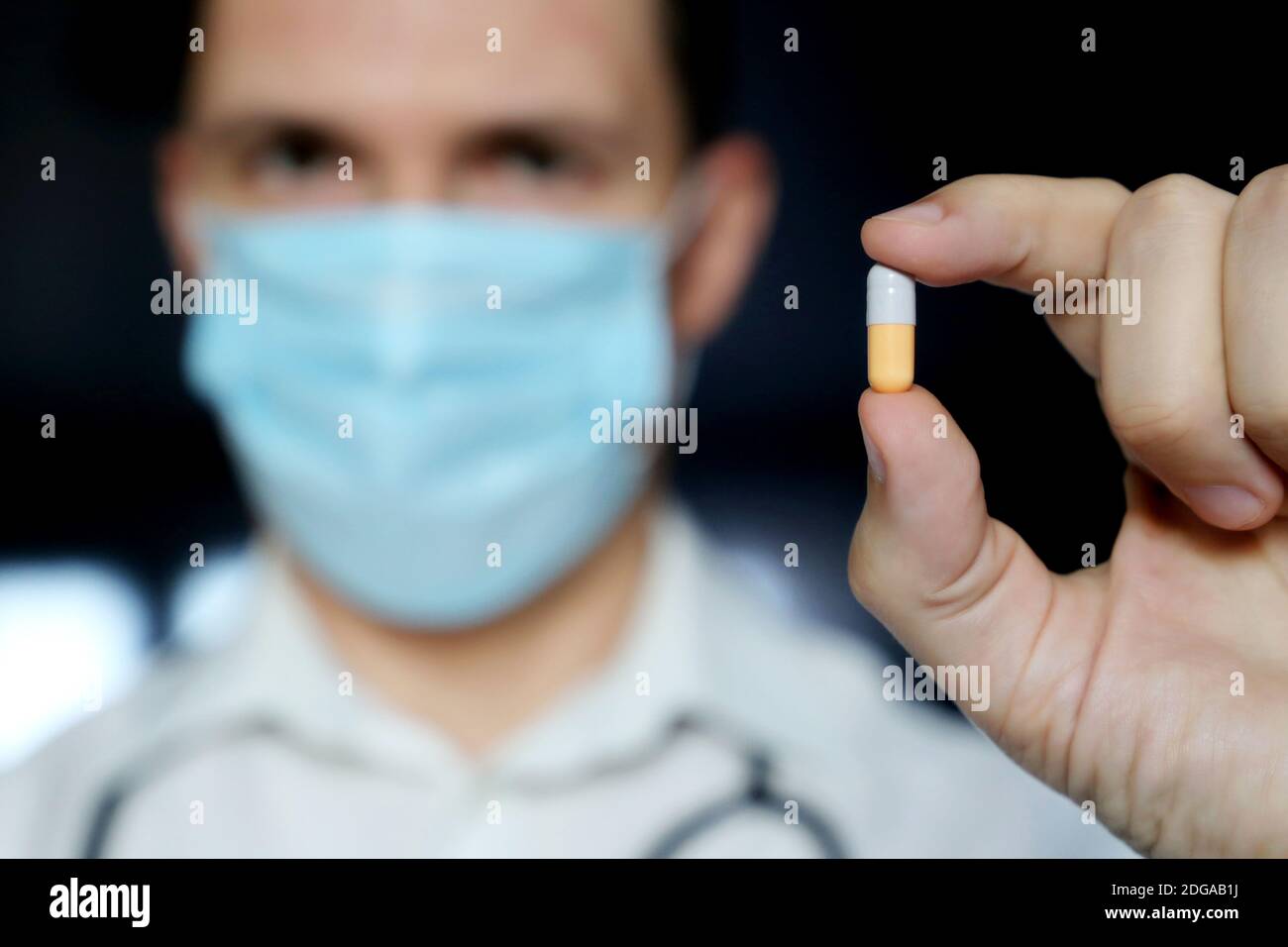 Doctor in medical mask holding pill, male hand with medication in ...