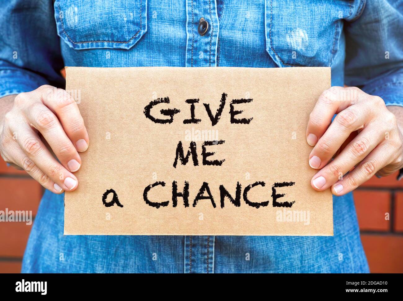 Woman hands holding piece of cardboard with words Give Me a Chance ...