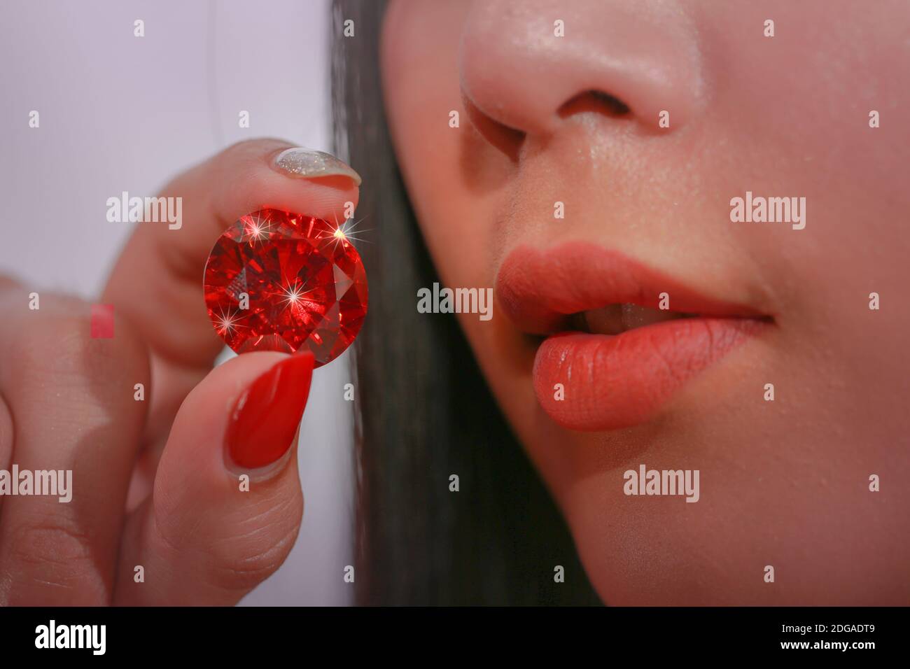 A lady Use your fingers to hold the red ruby diamond close to her lip ...