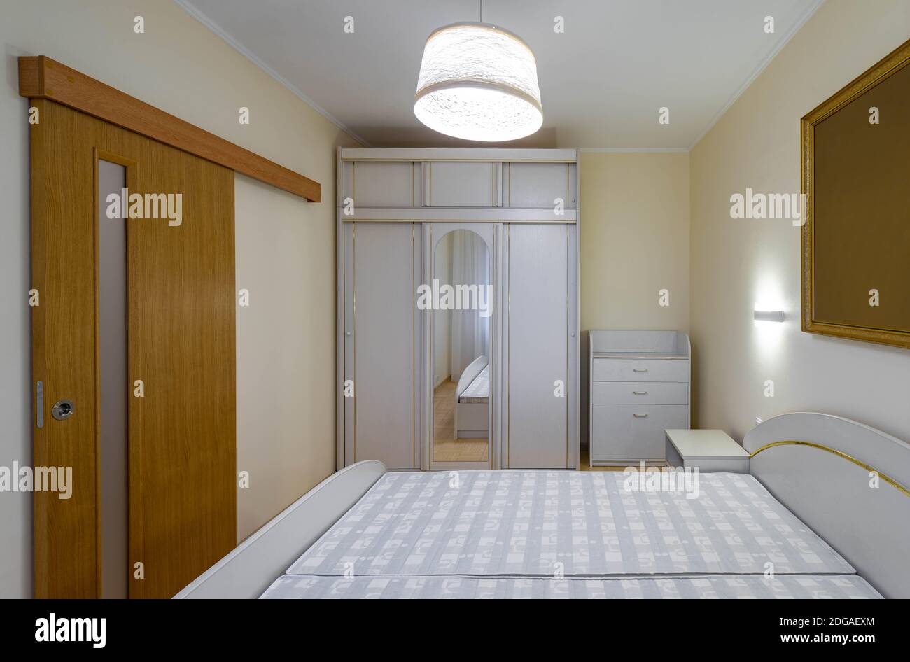 Modern interior of bedroom. Side view of bed. White wardrobe with ...