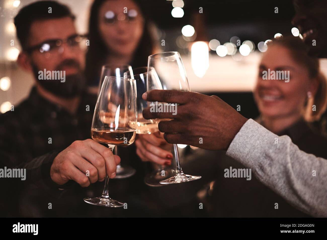 Diverse group of friends toasting together with drinks in a kitchen ...