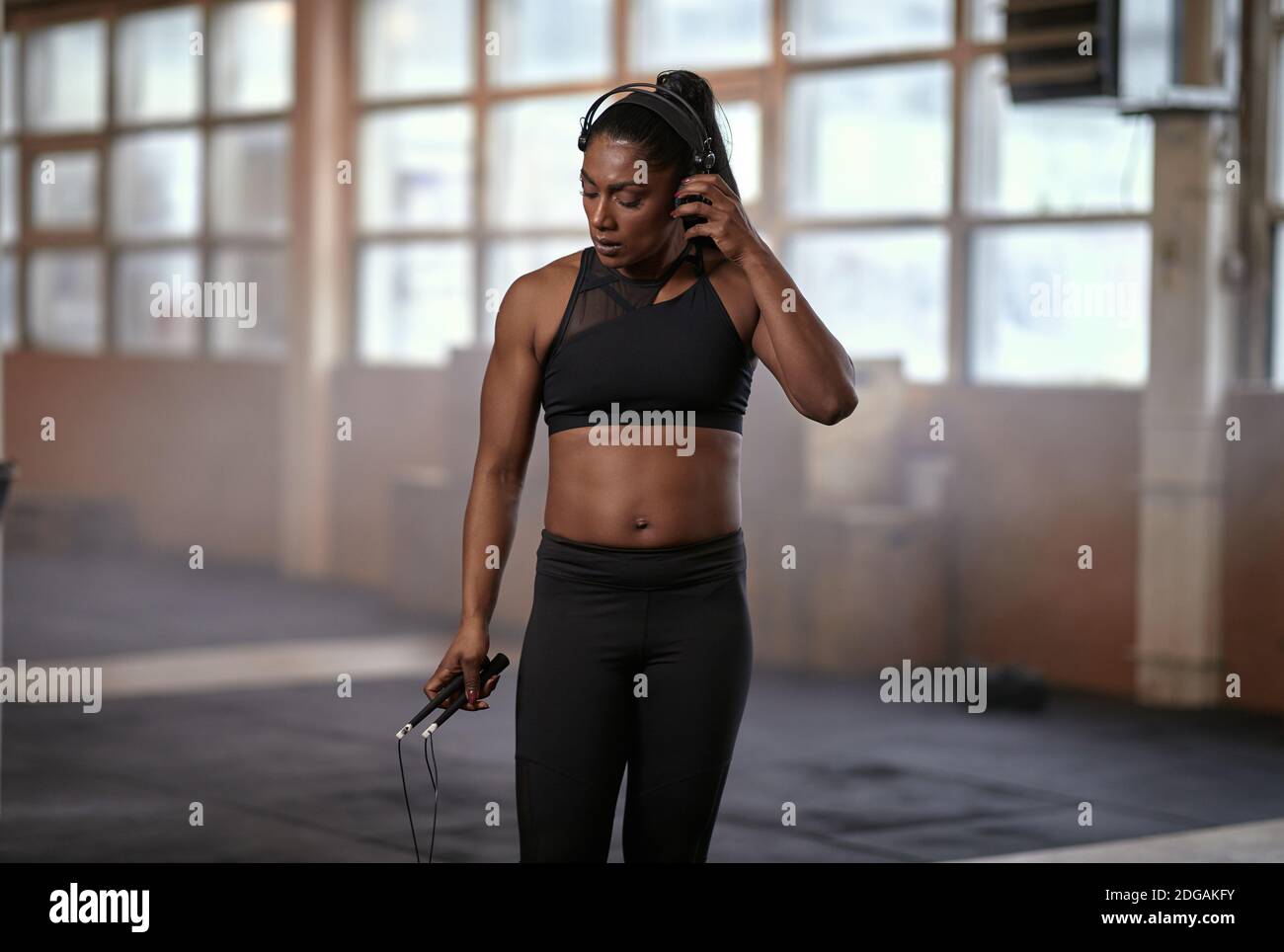 Exhausted ethnic lady in sportswear and with jumping rope breathing ...